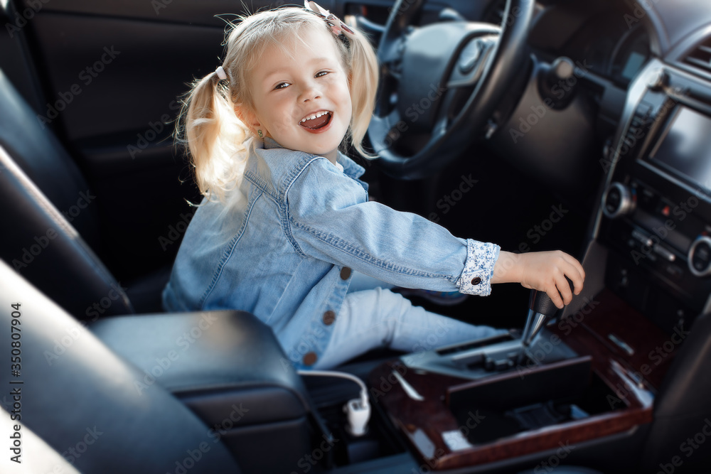 Cute little girl behind wheel of car.Baby girl sitting on the driver's ...