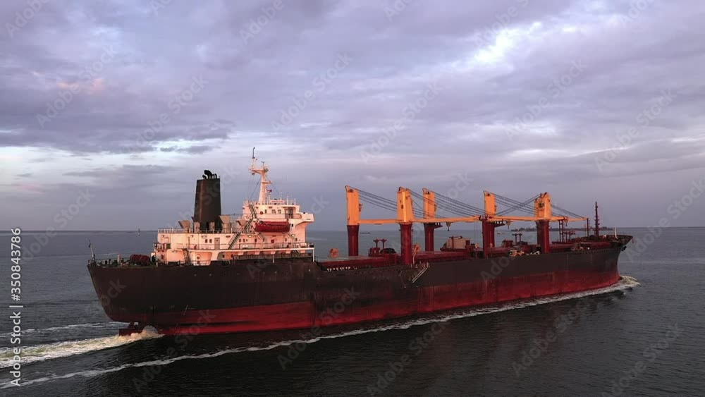 Aerial of merchant cargo bulker dispatch from seaport with wheat, ore ...