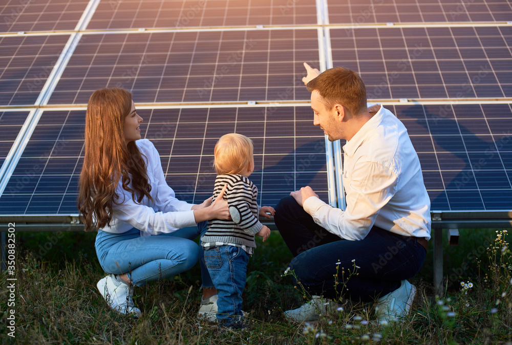 Father shows his family the solar panels on the plot near the house ...