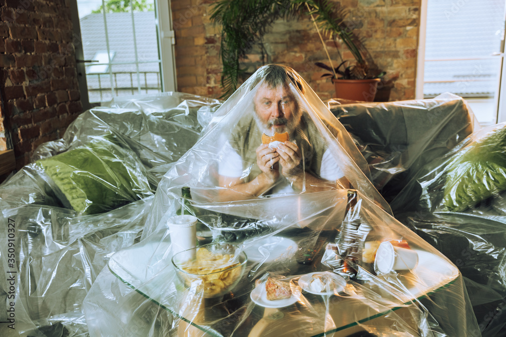 Senior man covered with plastic, eating fast food - environmental ...