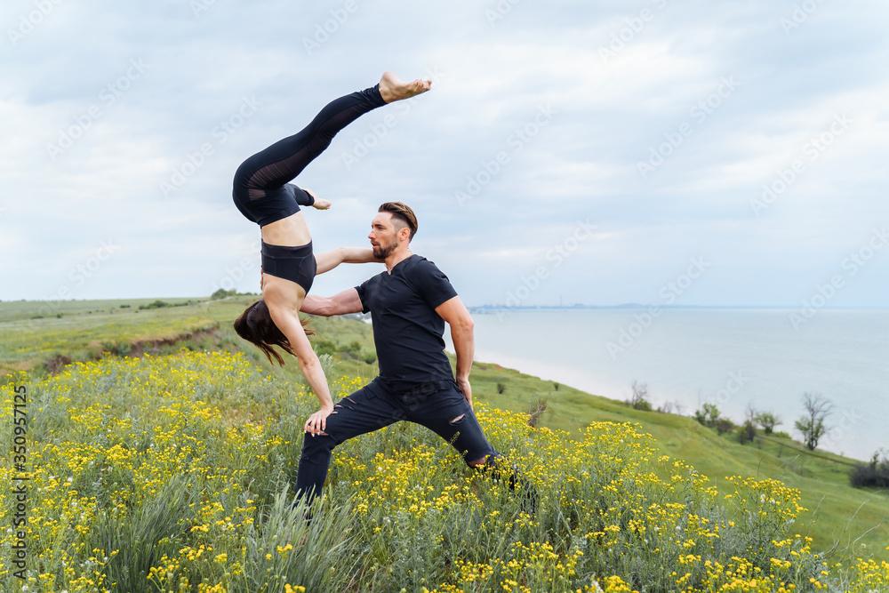 Couple practicing acro yoga poses outdoors outside. Pair of sportsmen ...