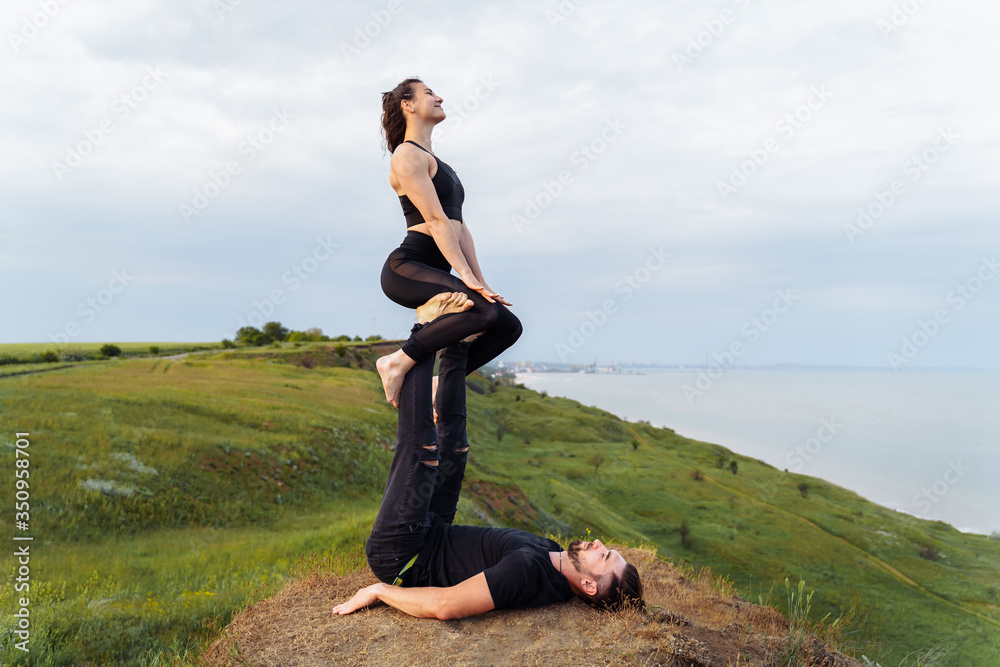 Acroyoga posture straddle throne. An athletic couple of sportsmen doing ...