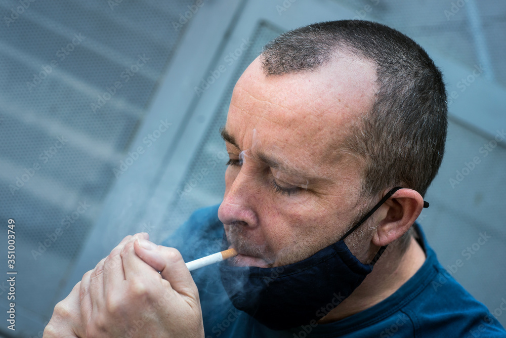 Portrait of caucasian man smoking a cigarette with a homemade fabric ...