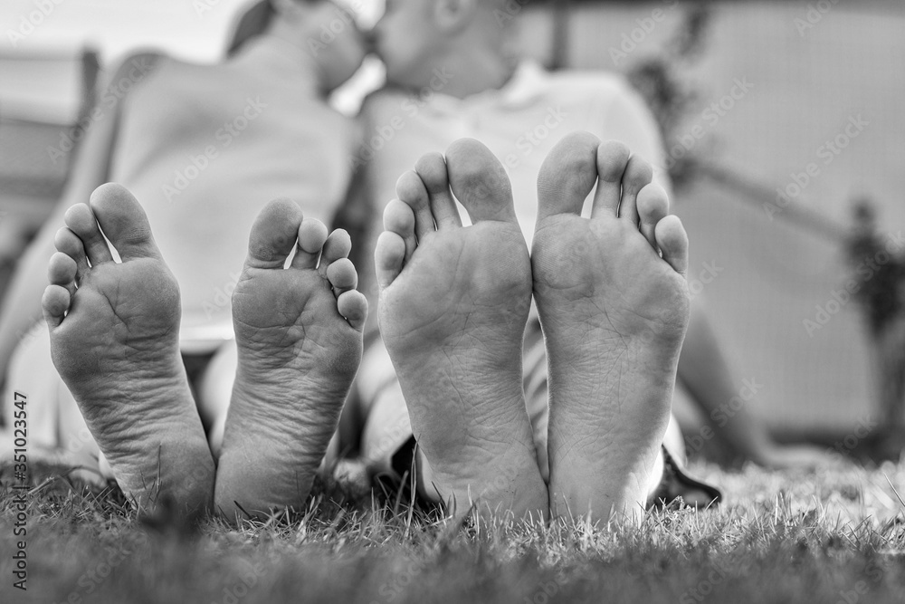 Romantic young couple kissing in the garden. Family feet in focus. Feet ...