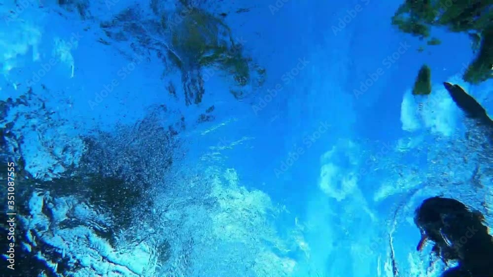 Underwater video looking up at man and woman swimming in the pool. Blue ...