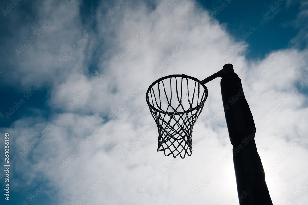 Netball goal ring and net against a blue sky and clouds at Hagley park ...