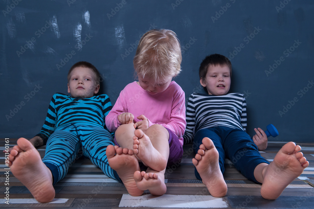 Three children are sitting on floor in room and are going to do ...