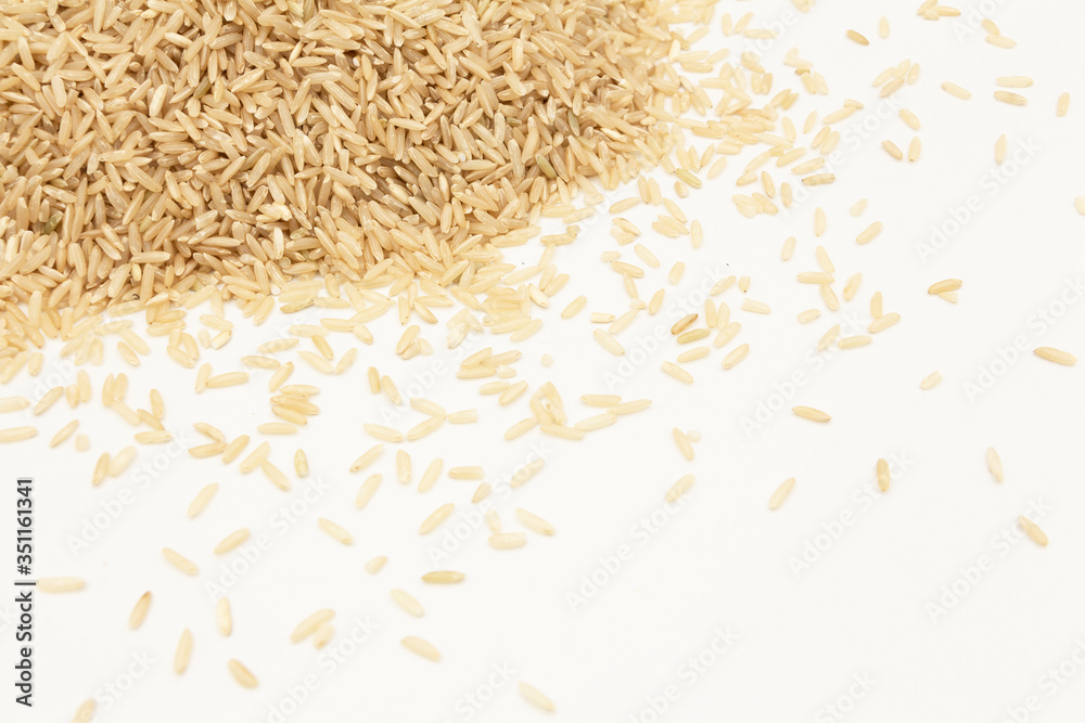 Half a pile of long-grain, brown rice on a white background lies in the ...