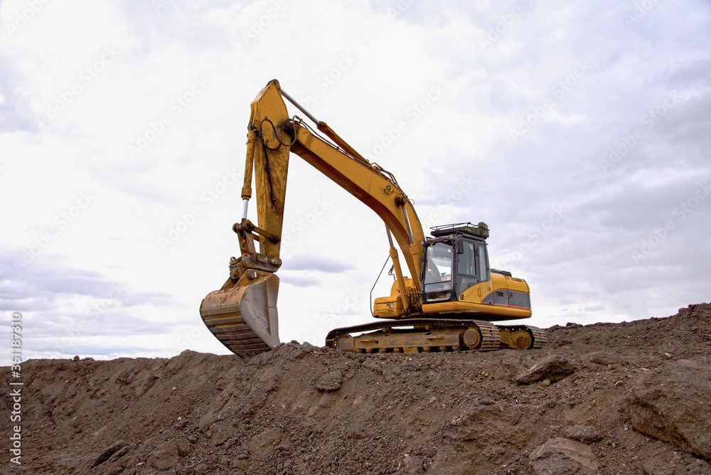 Excavator working on earthmoving at open pit mining on sunset ...