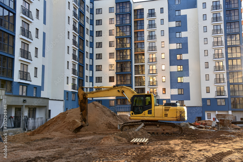 Yellow excavator in action at a construction site on the background of ...