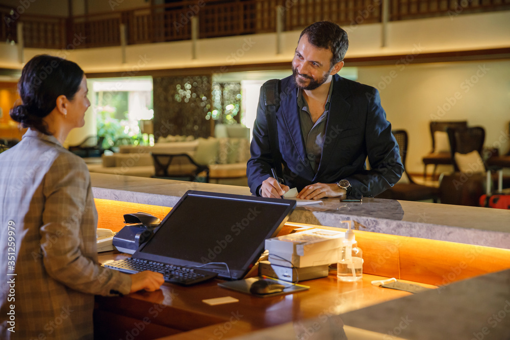 Businessman checking in at hotel. Young handsome man and receptionist ...