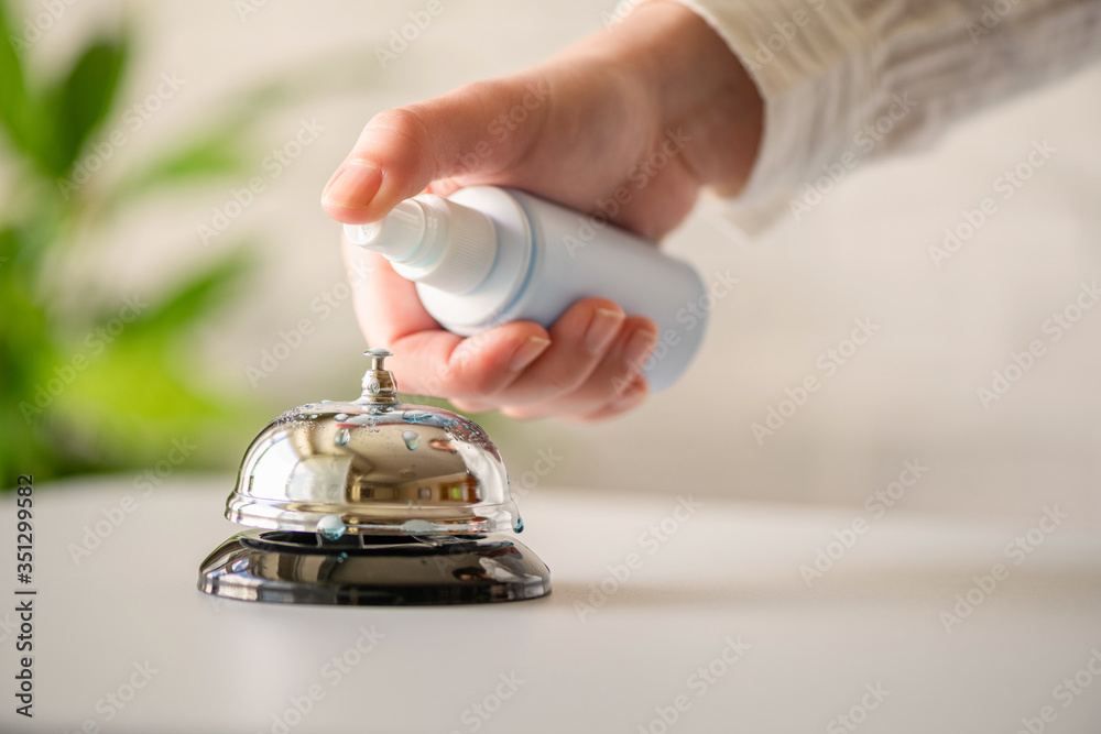 Hand of woman cleaning ringing bell on reception desk. disinfection ...