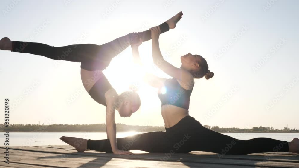 Two kid girls do pair acroyoga, support gymnastics position, perform ...