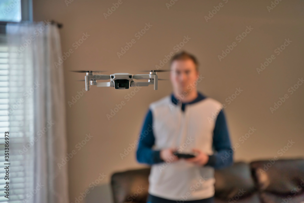 Drone flying indoors with pilot visible in background. Amateur drone ...