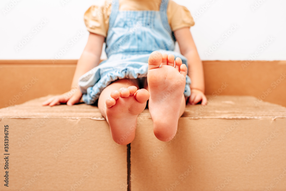 Bare feet of a girl sitting on a pile of cardboard. Stock Photo | Adobe ...