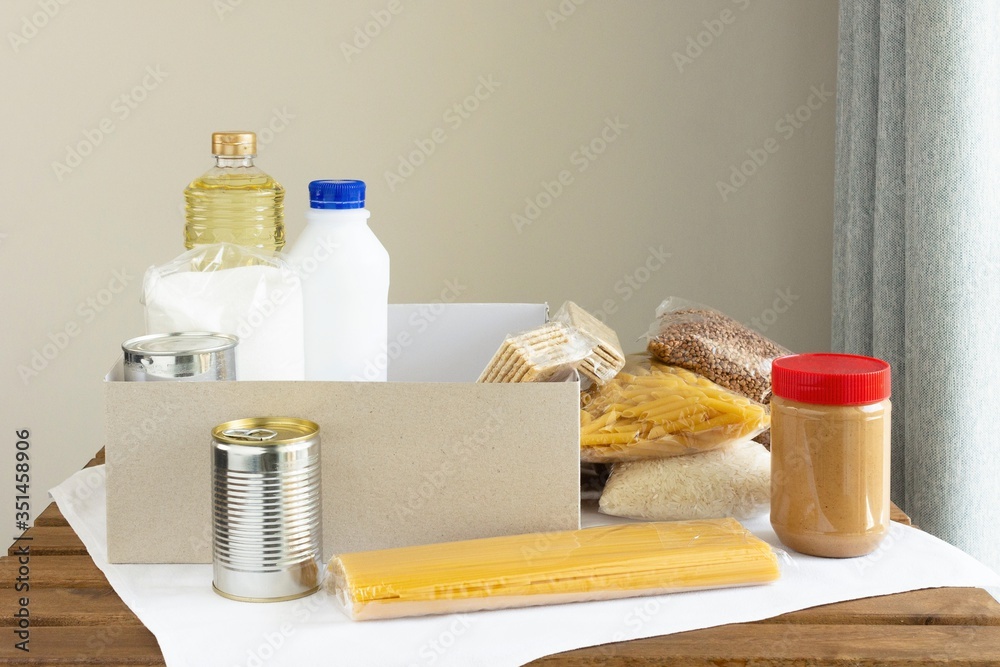 Cardboard box with food on wood table and white napkin. Donation and ...