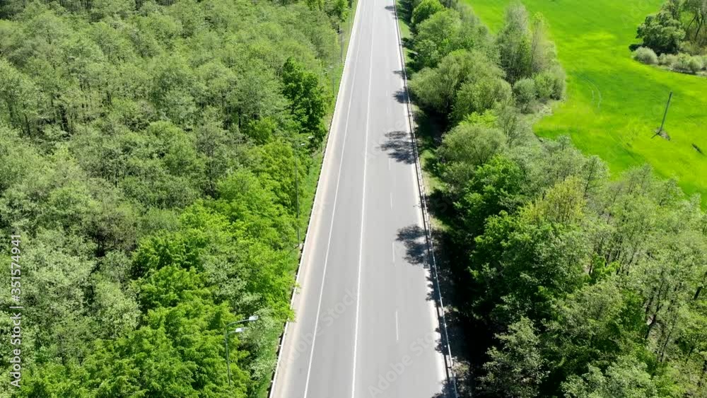 Empty road without cars. The highway goes through fields and forests ...