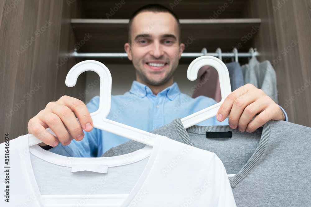 Attractive man in wardrobe chooses his clothes, a guy with clothes in ...