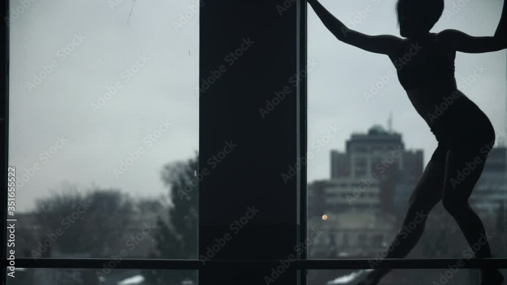 Vidéo Stock Modern dancer dances in front of large window in silhouette ...