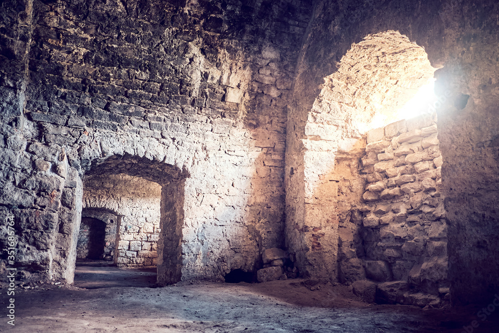 Ancient stone basement with arches. The sun breaks through window. Long ...