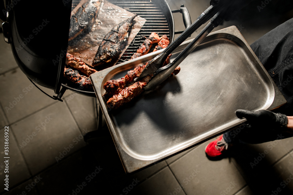 Top view how male chef puts fried pieces of beef meat from grill to ...