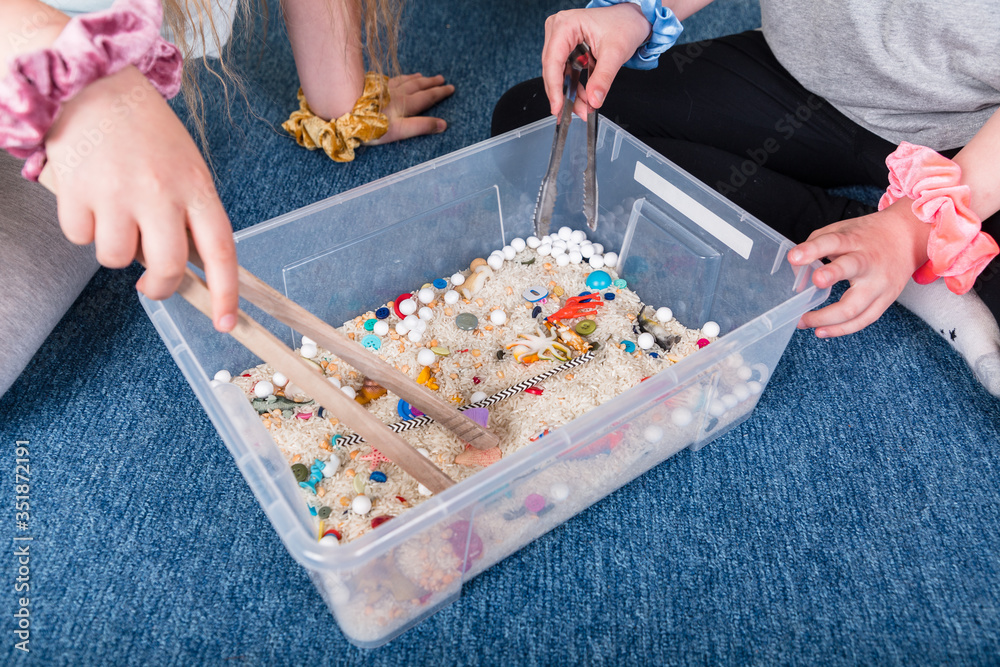 Foto Stock Sensory integration therapy - picking up small objects with tongs from a rice ...
