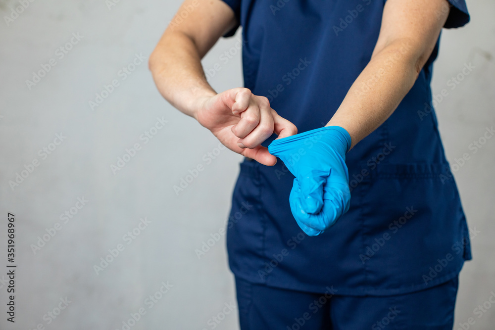 A medical health care worker woman in navy blue scrubs taking off her ...