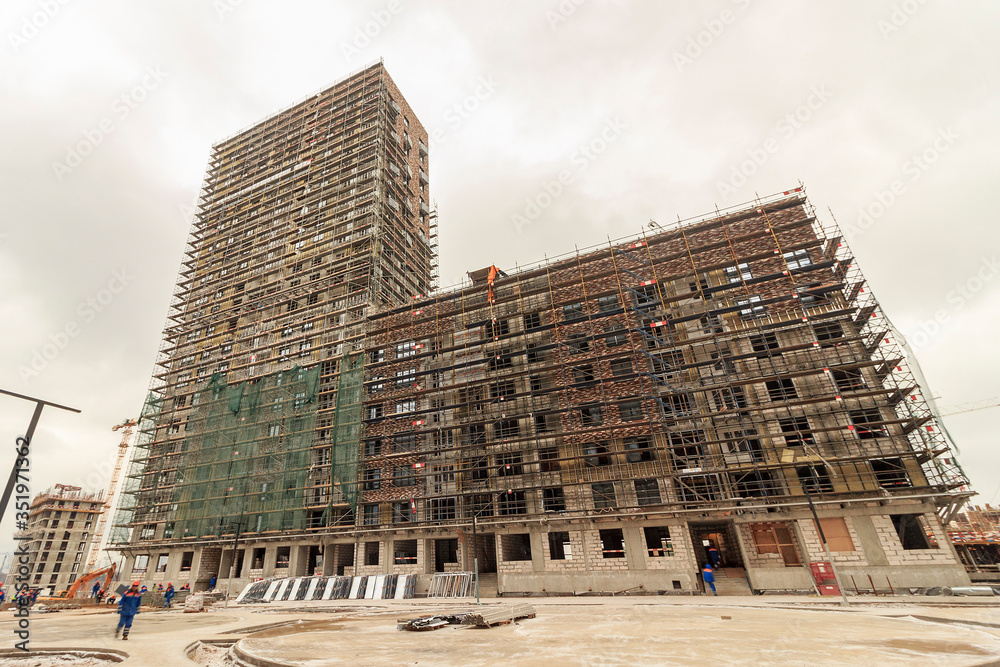Tall building under construction with scaffolds. Construction site ...