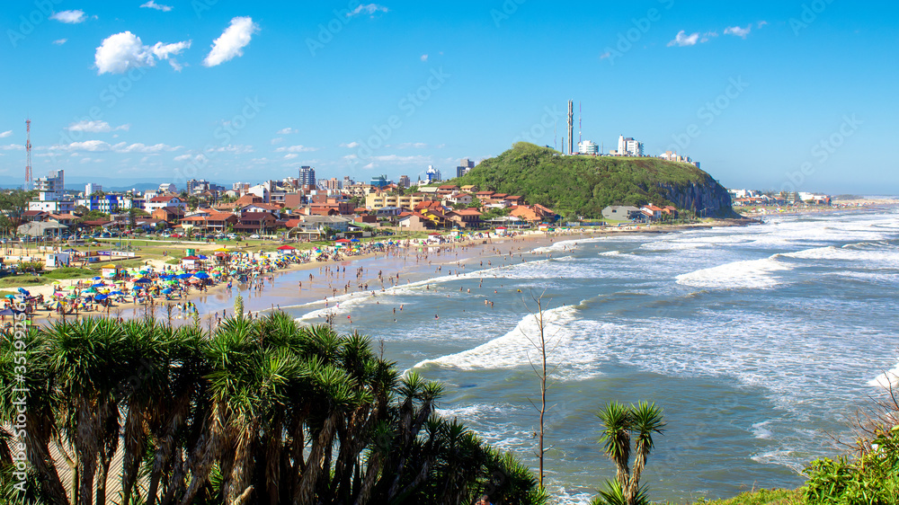 Ondas, mar, vegetação, areia e praia cheia em dia de sol na prais ...