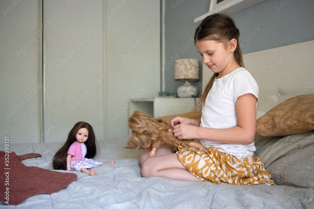 Caucasian girl combing a doll with long hair, a girl playing dolls ...