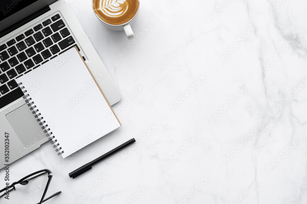 Blank notebook is on top of laptop computer over white marble office ...