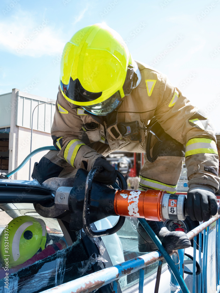 Firefighter using rescue tool to cut vehicle in rescue by traffic ...