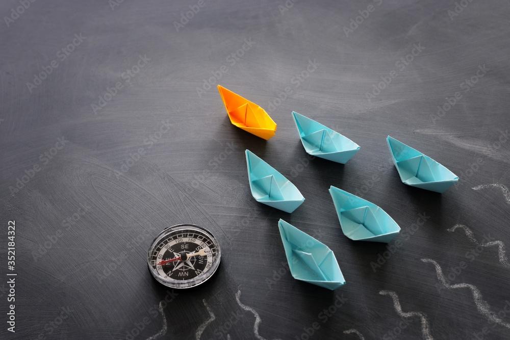 Leadership banner concept with paper boat on blackboard background. One ...