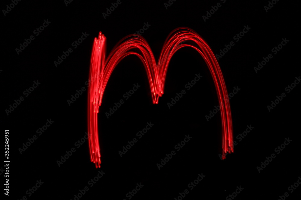 Long exposure photograph of the letter m in neon red colour fairy ...