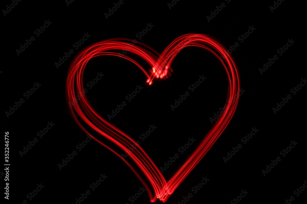 Long exposure photograph of neon red colour in an abstract heart shape ...