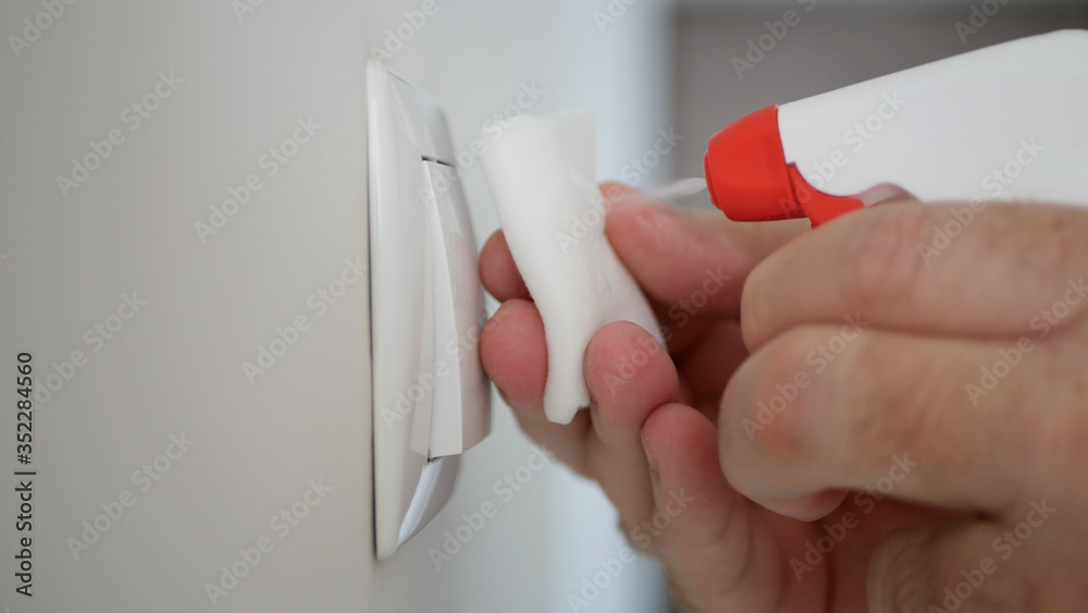 Man Cleaning and Disinfecting Light Switch from the Office Room Using ...
