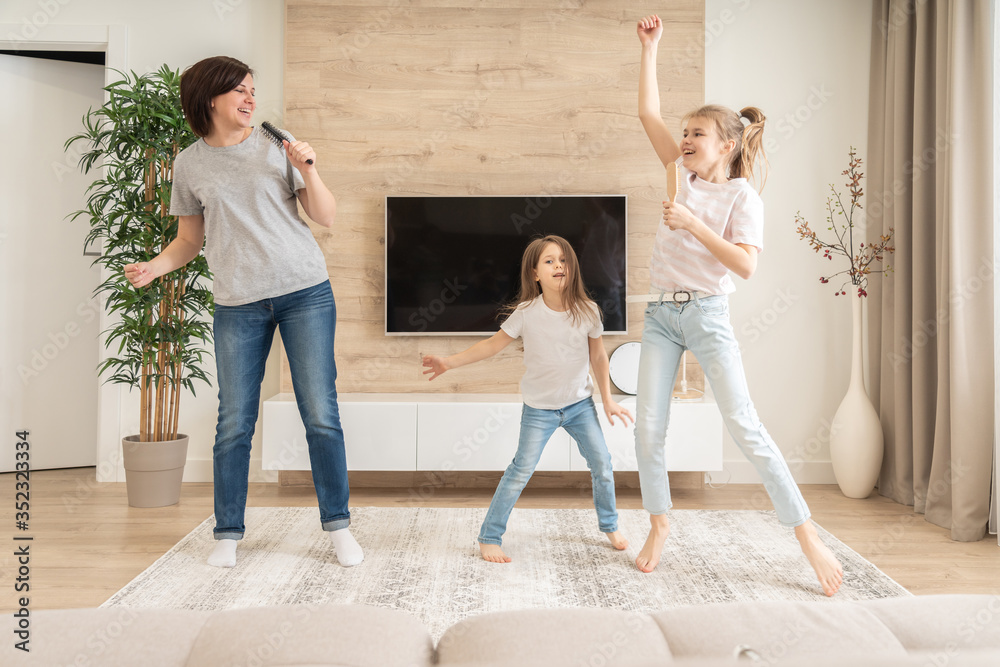Happy mother and two daughters having fun singing karaoke song in ...