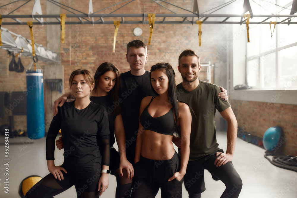 One team, one mission. Sportive people in black sportswear looking at ...