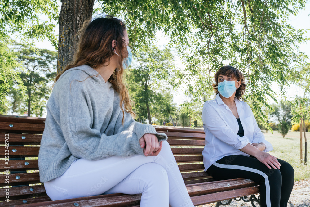 Social distance. Mother and daughter in social distance sitting on a ...
