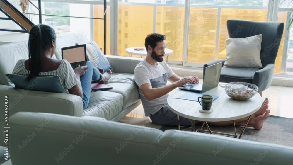Multiethnic couple working or playing with laptop computers at home ...