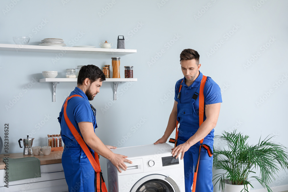 Loaders carrying washing machine by using cargo belts Stock Photo ...