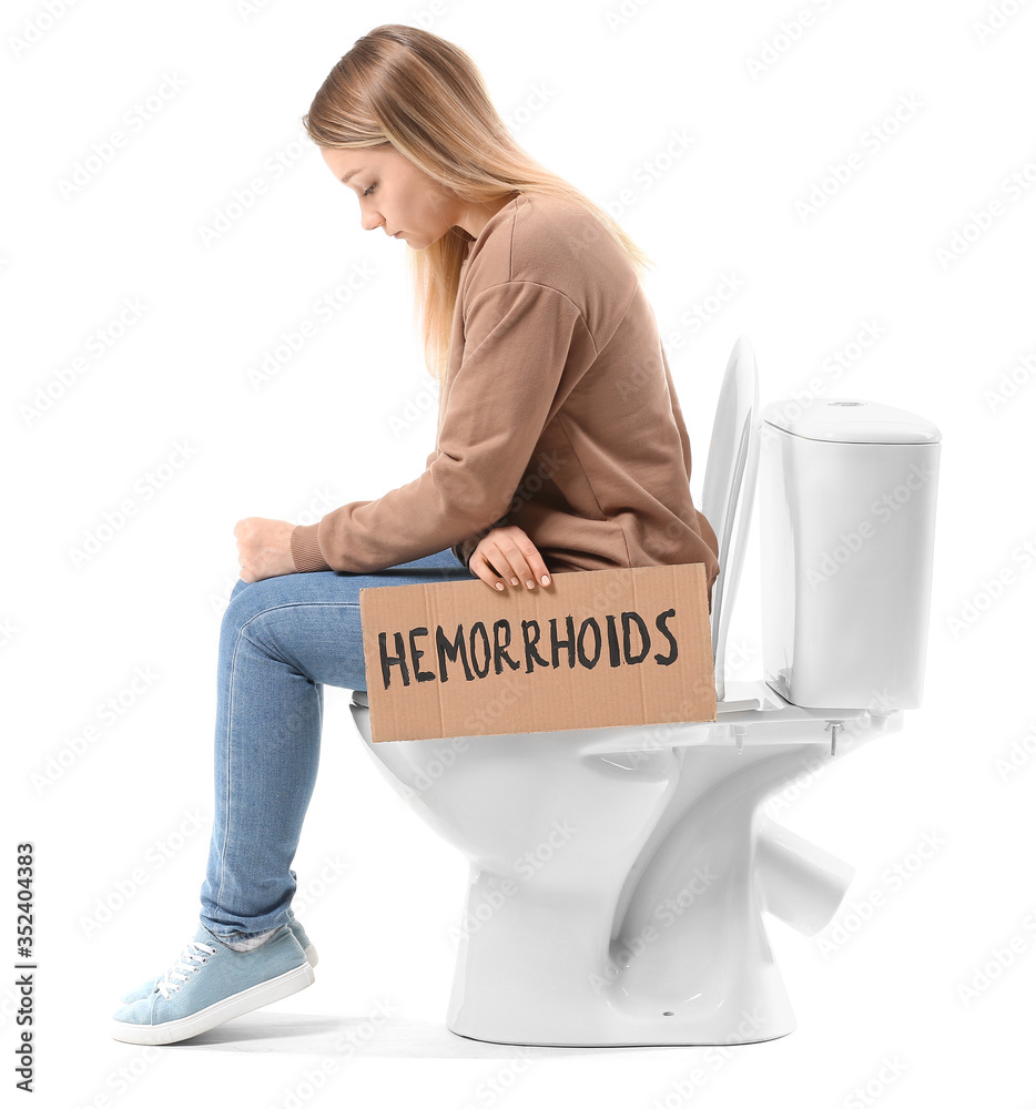 Young Woman Sitting On Toilet Bowl Against White Background