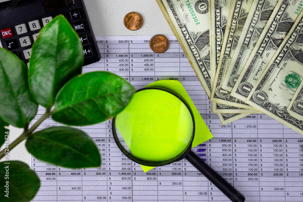 Foto de Money, post-it note, magnifier, calculator and on the desktop ...