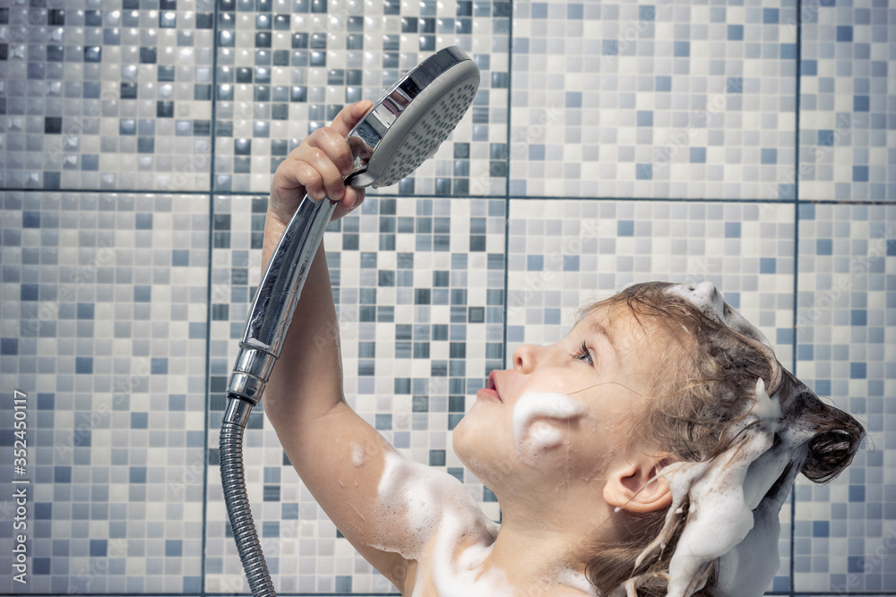a little girl in foam is standing in the bathtub in her hand holding a ...