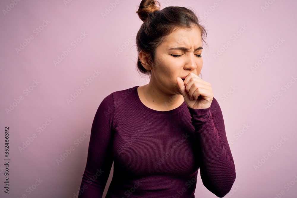 Beautiful young woman wearing casual bun hairstyle over pink isolated ...