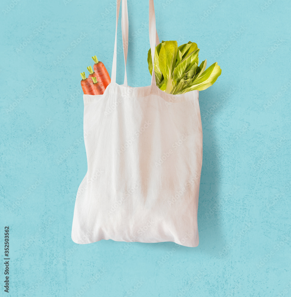 White textile grocery shopping bag with vegetables hanging at light ...