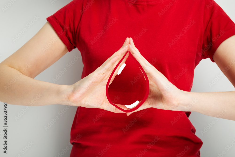 Young girl in red T-shirt shows her hands drop on grey background ...