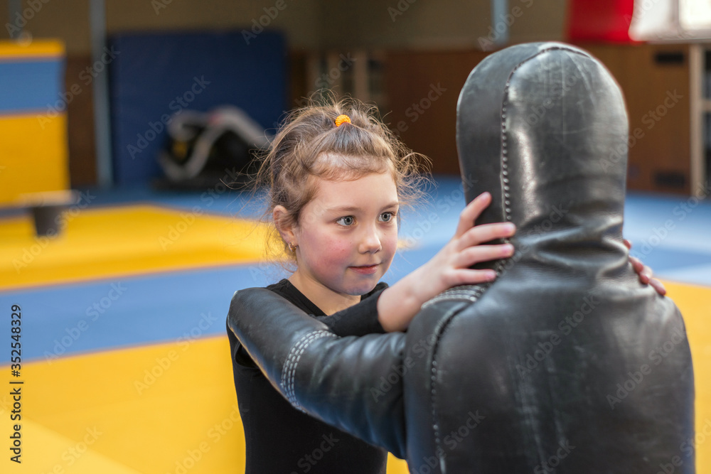 The little girl is engaged in martial arts with a training manikin. The ...