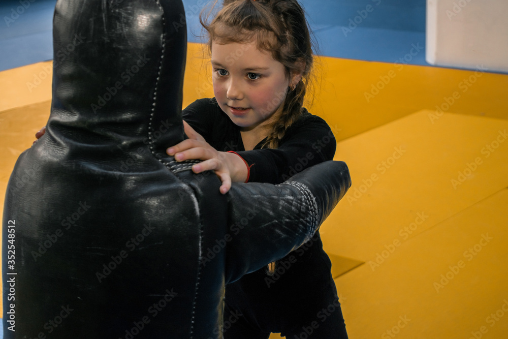 The child is practicing fighting techniques on the simulator in the gym ...