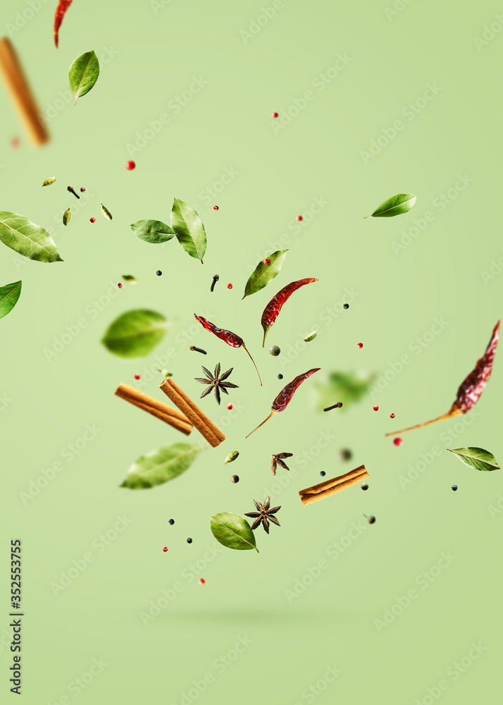 Flying spices bay leaf, red chili pepper, anise, cinnamon sticks on a ...